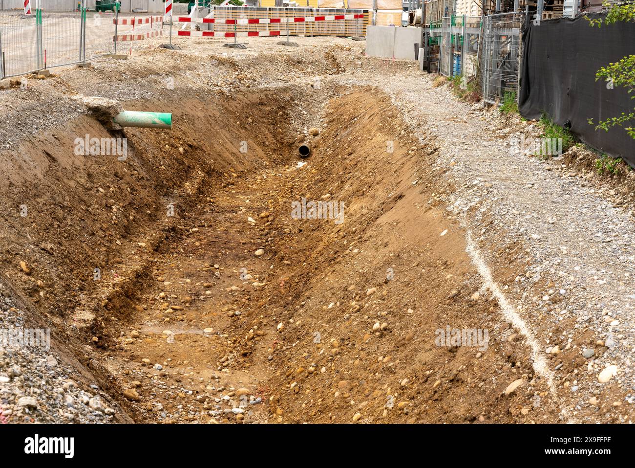 Excavator hole with pipes protruding into the hole from two sides ...