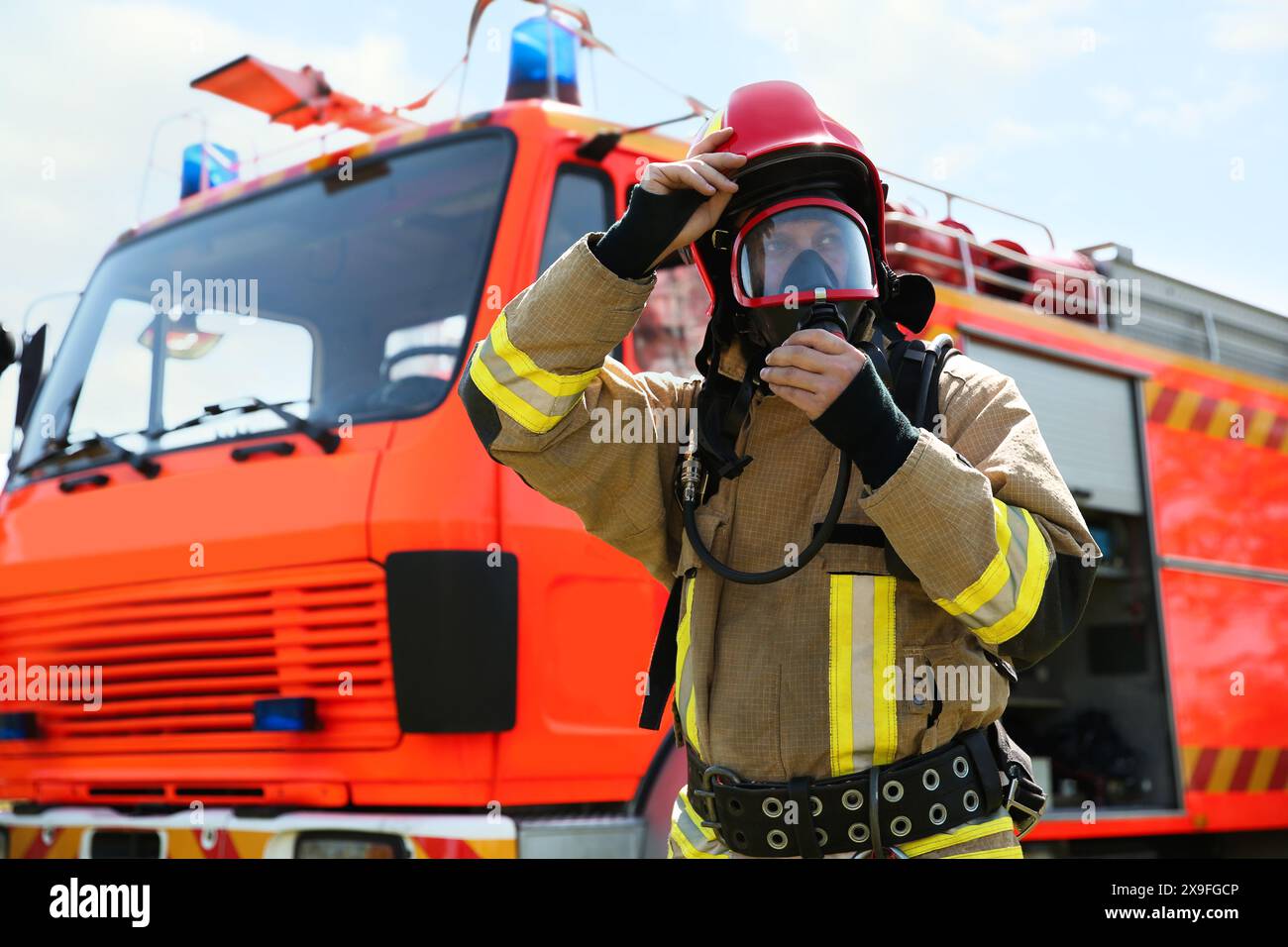 Firefighter in uniform wearing helmet and mask near fire truck outdoors ...