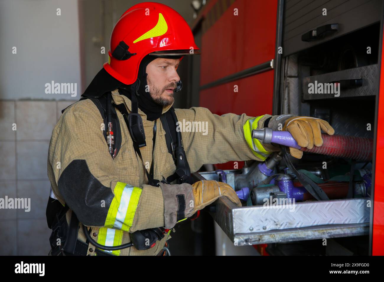 Firefighter in uniform with fire engine equipment at station Stock ...