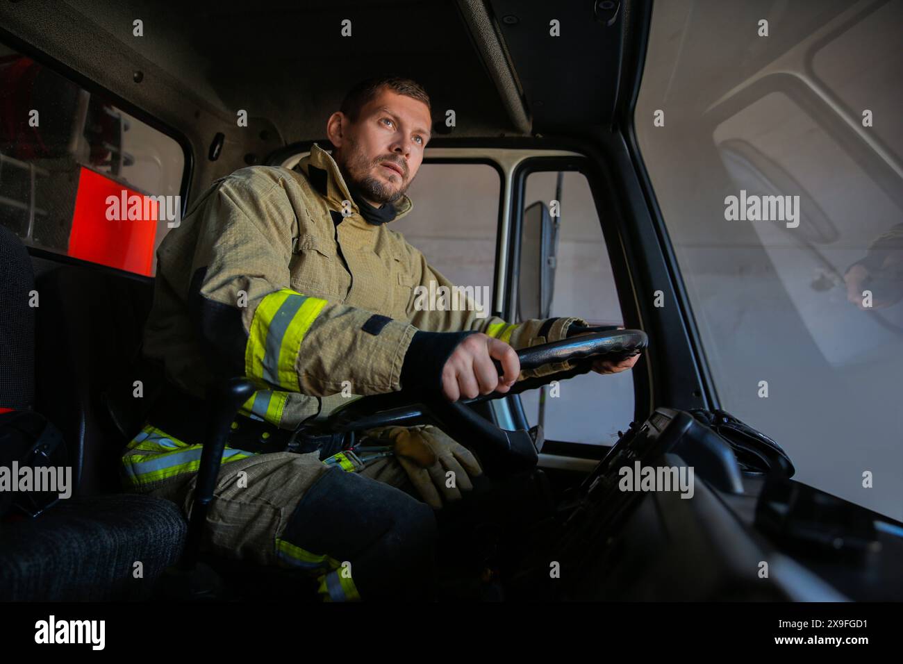 Firefighter in uniform driving modern fire truck Stock Photo - Alamy