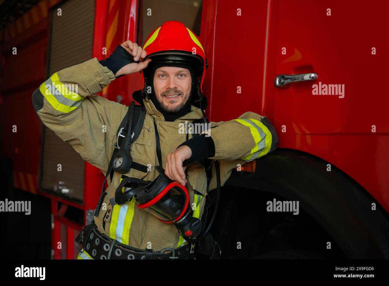 Portrait of firefighter in uniform near red fire truck at station Stock ...