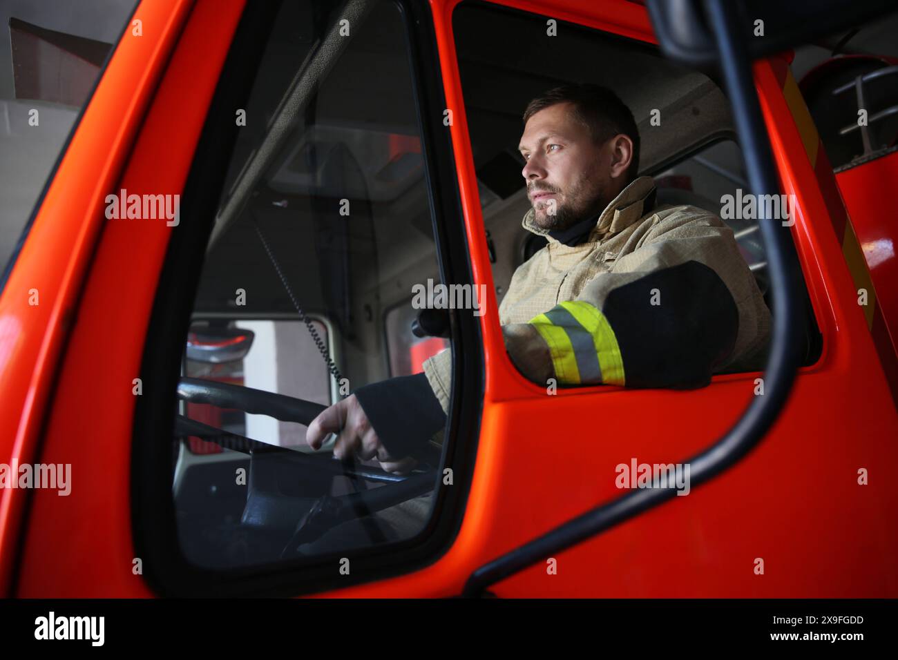 Firefighter in uniform driving modern fire truck Stock Photo - Alamy