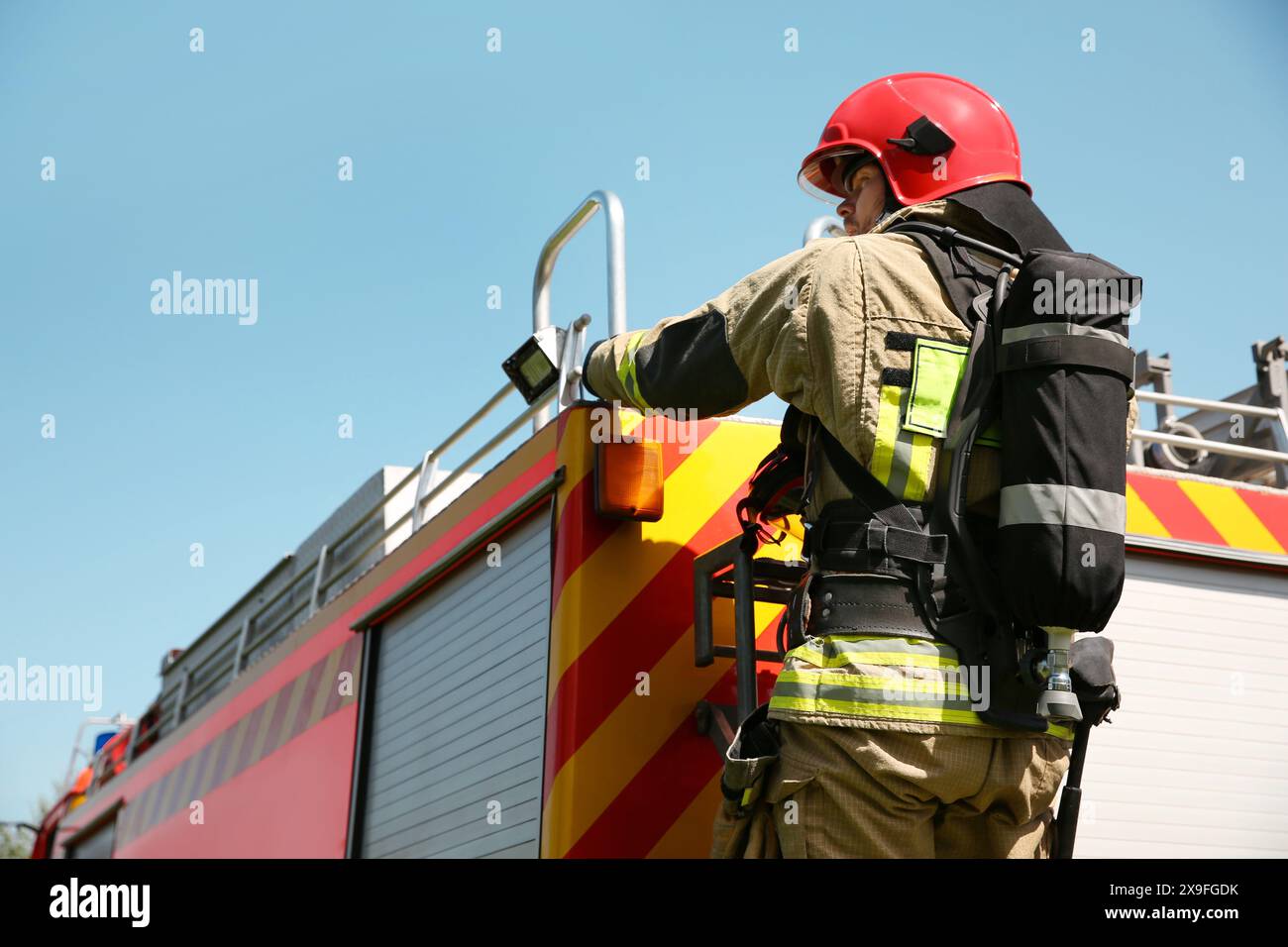 Firefighter in uniform on fire truck outdoors, back view Stock Photo ...