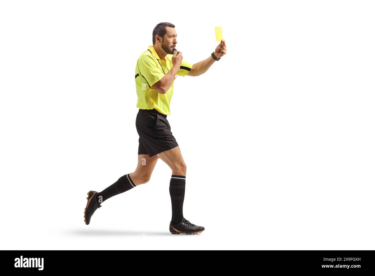 Full length profile shot of a football referee running and showing a ...