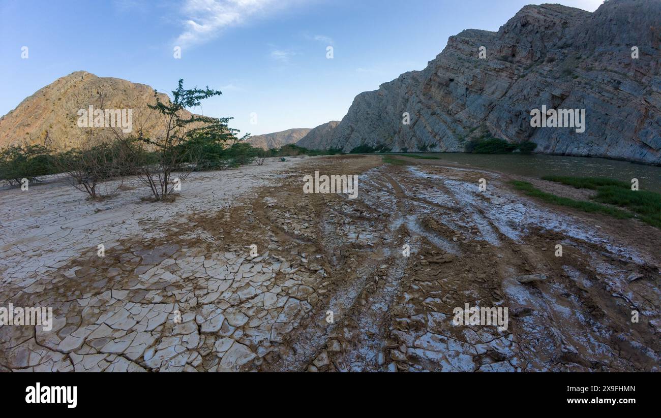 Photography of dried up riverbed with mud and tyre tracks next to a ...