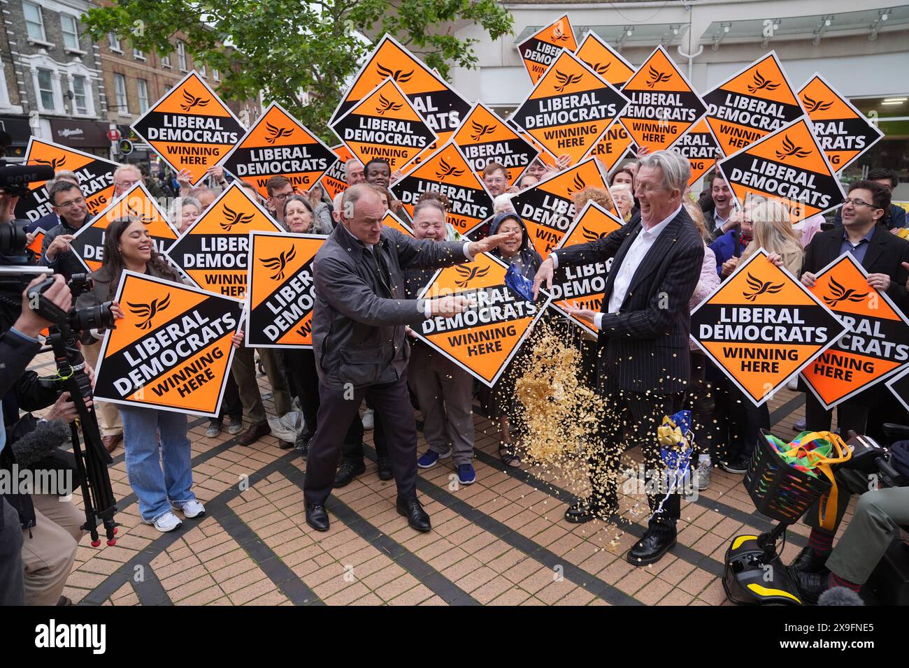 Liberal Democrats leader Sir Ed Davey pops a balloon standing next to ...