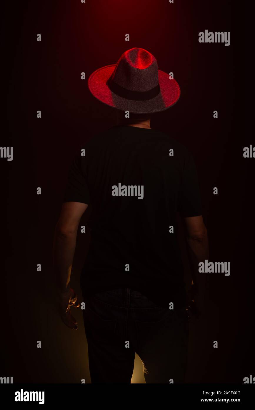 Mysterious man wearing hat standing with his back to the camera. Studio ...