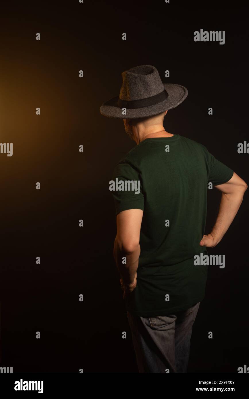 Mysterious man wearing hat standing with his back to the camera. Studio ...