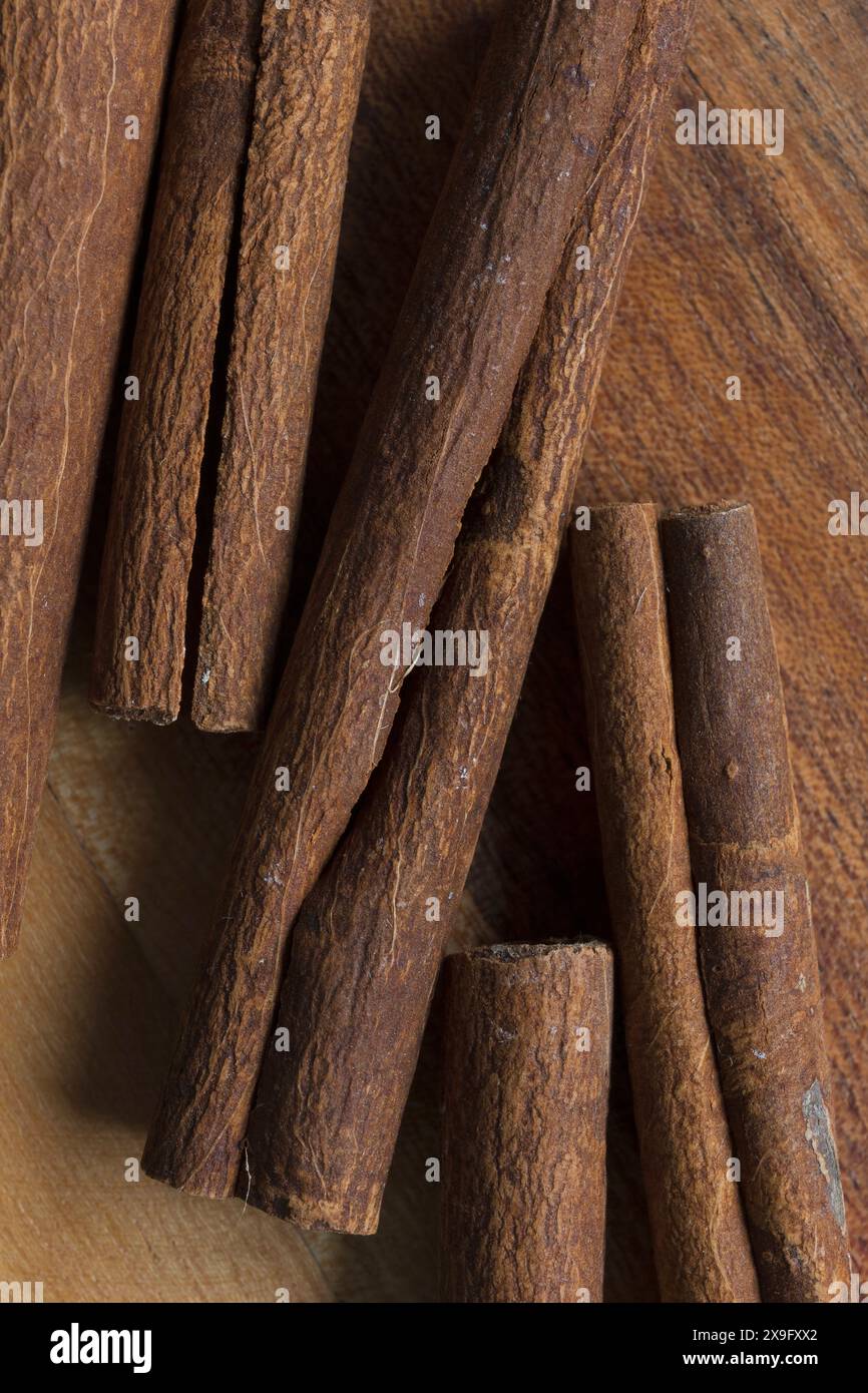 Flat lay close-up food photography of cinnamon sticks on an acacia cutting board, aromatic ...