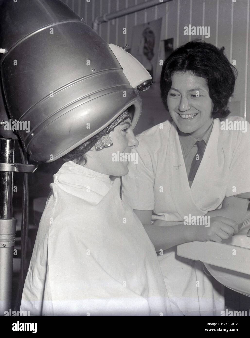 1950s, historical, a young lady in a hair salon, her hair in curlers ...