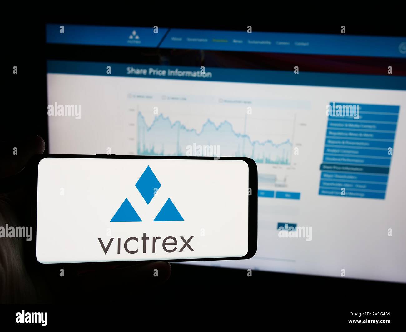 Person holding mobile phone with logo of British polymer production ...