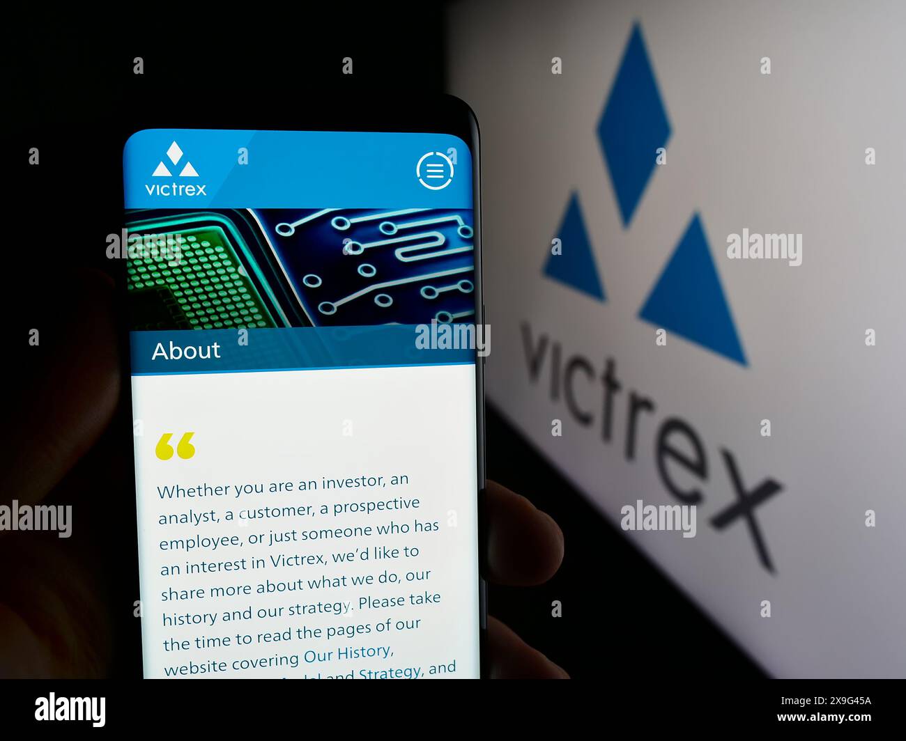 Person holding cellphone with webpage of British polymer production ...