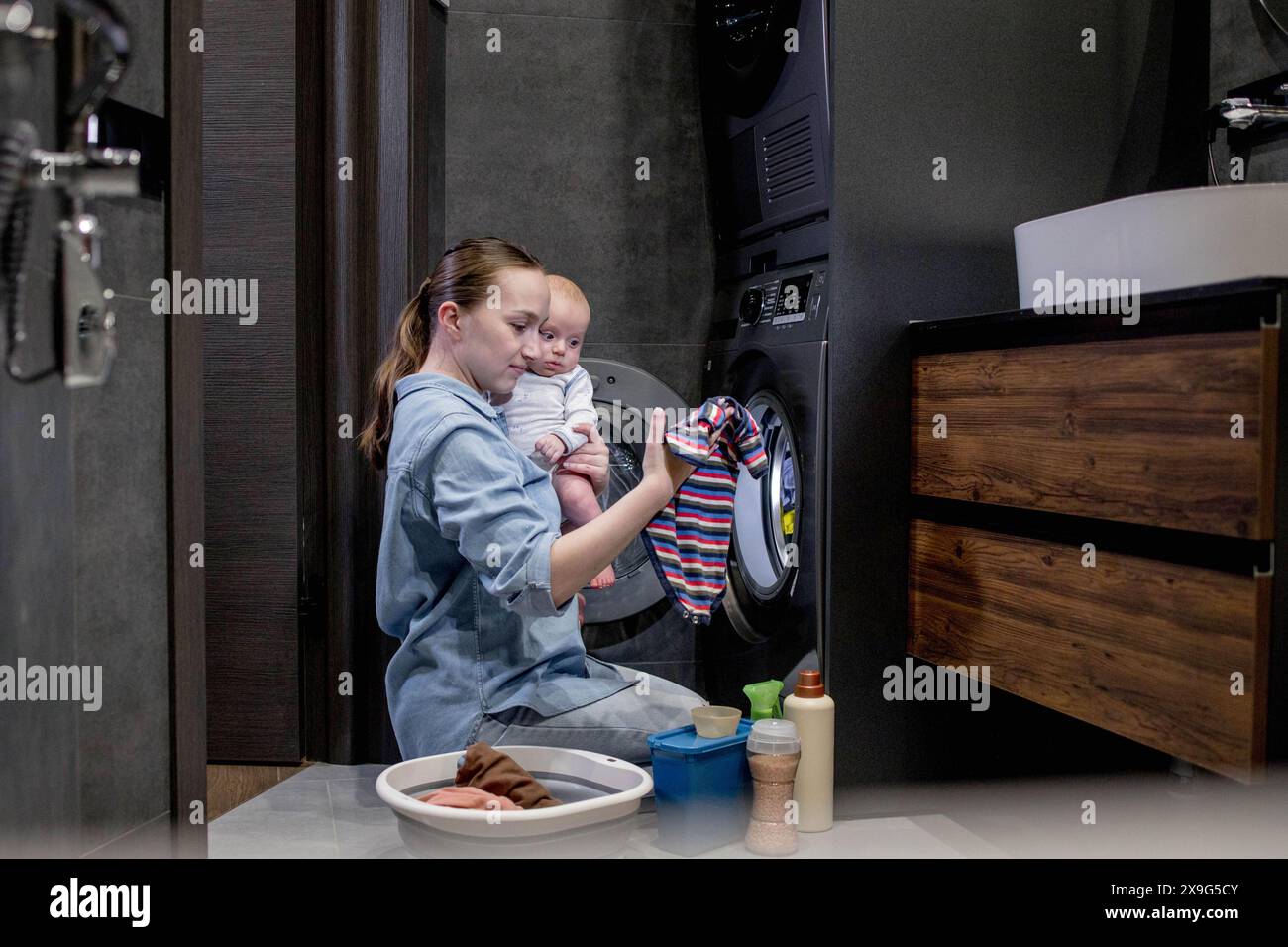 Washing children's clothes. A woman does housework with a child in her ...