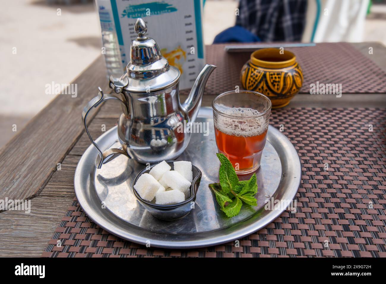 Traditional Moroccan mint tea iced with white sugar cubes is a popular ...