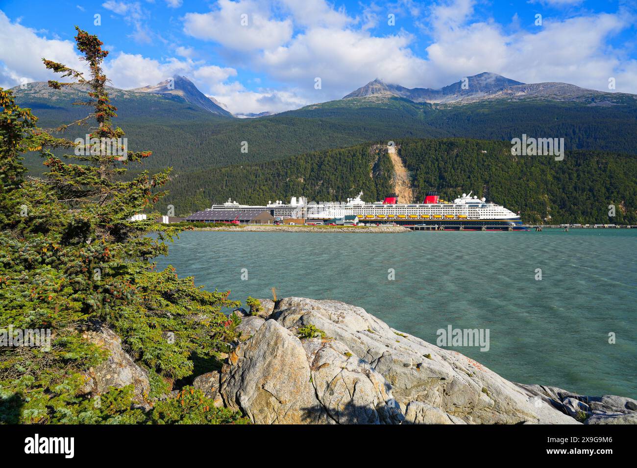 Cruise ships moored in the port of Skagway, surrounded by mountains in the Taiya Inlet ...