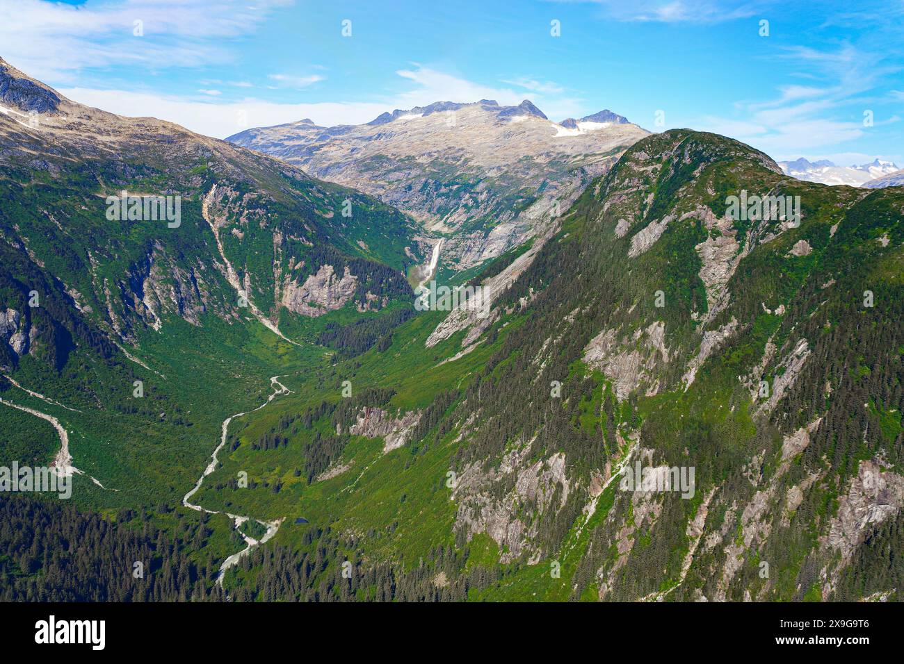 Aerial view of a waterfall flowing in a green valley along the Taku ...