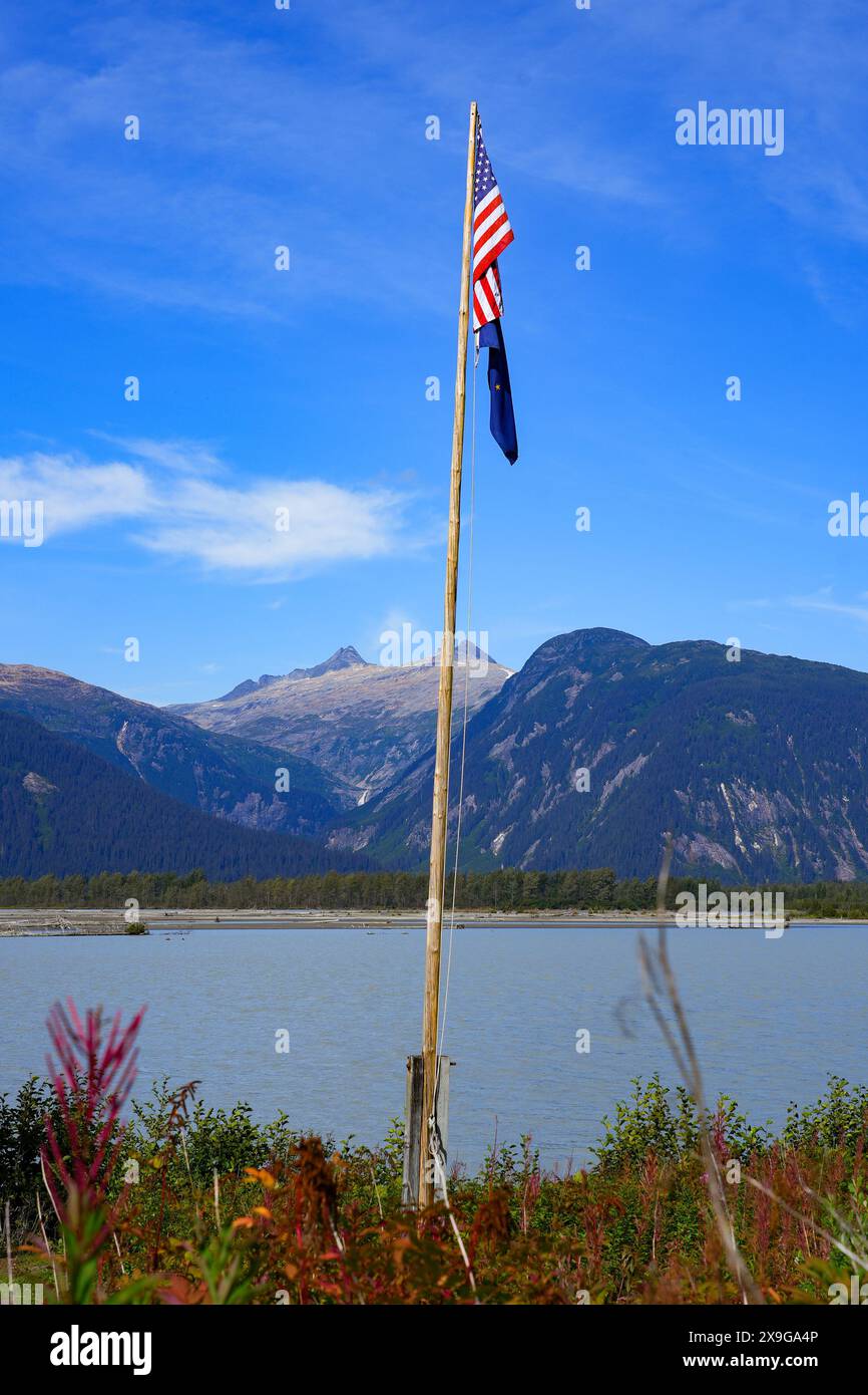 United States and Alaskan flags hanging at the top of a wooden flagpole ...