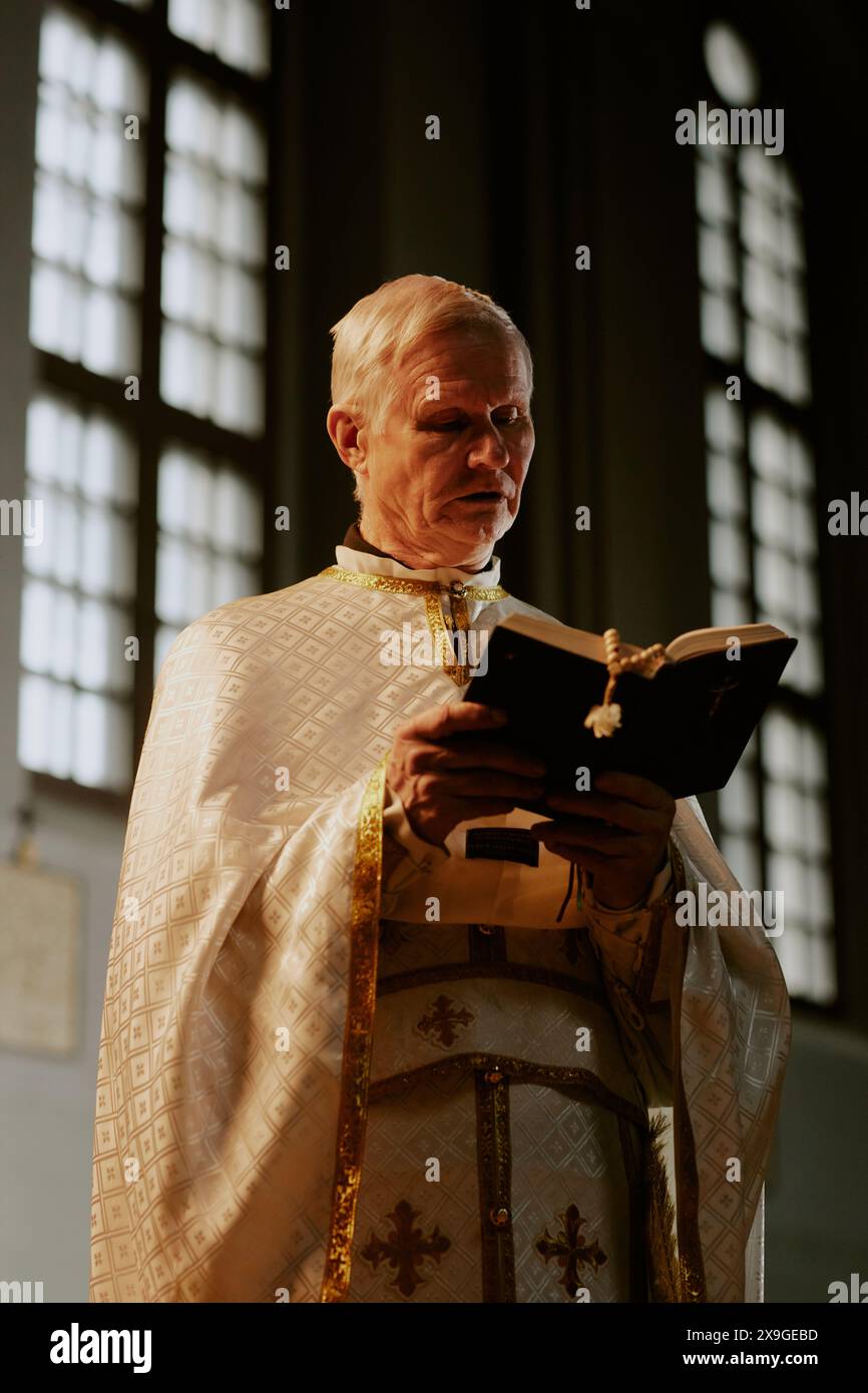 Vertical low angle medium shot of senior Catholic priest wearing ...