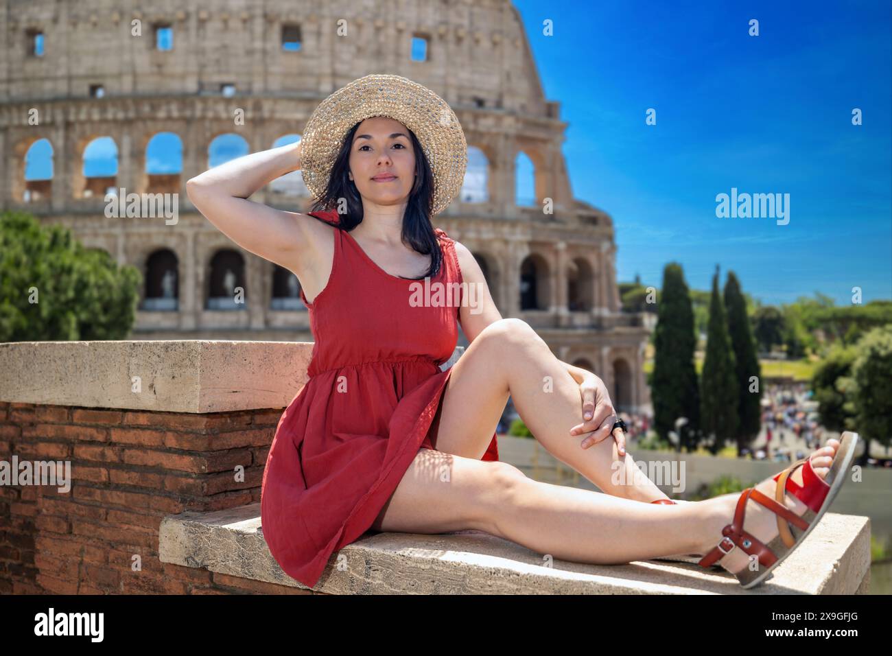 A brunette girl with a straw hat and red dress in front of the ...