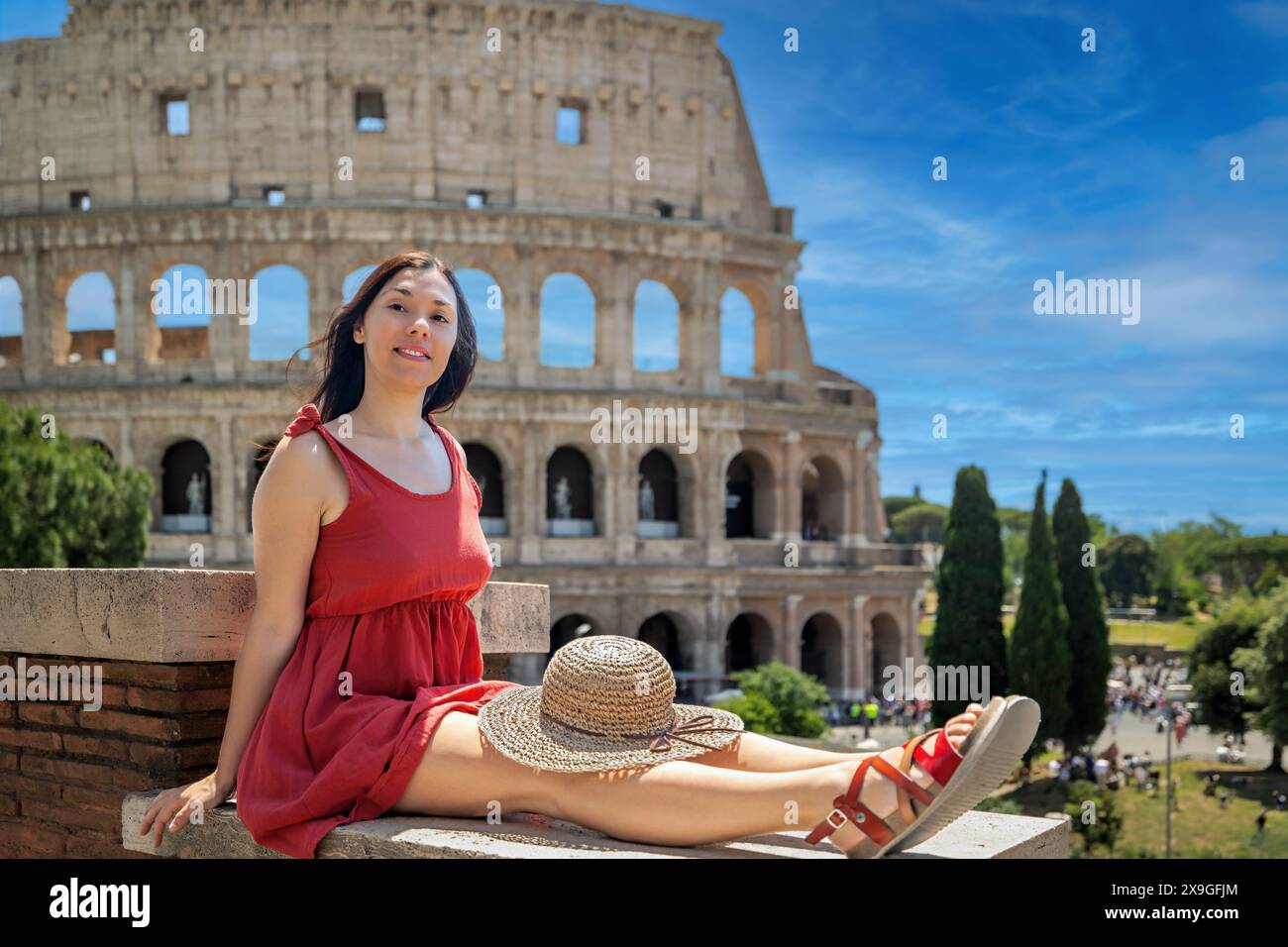 A brunette girl with a straw hat and red dress in front of the ...
