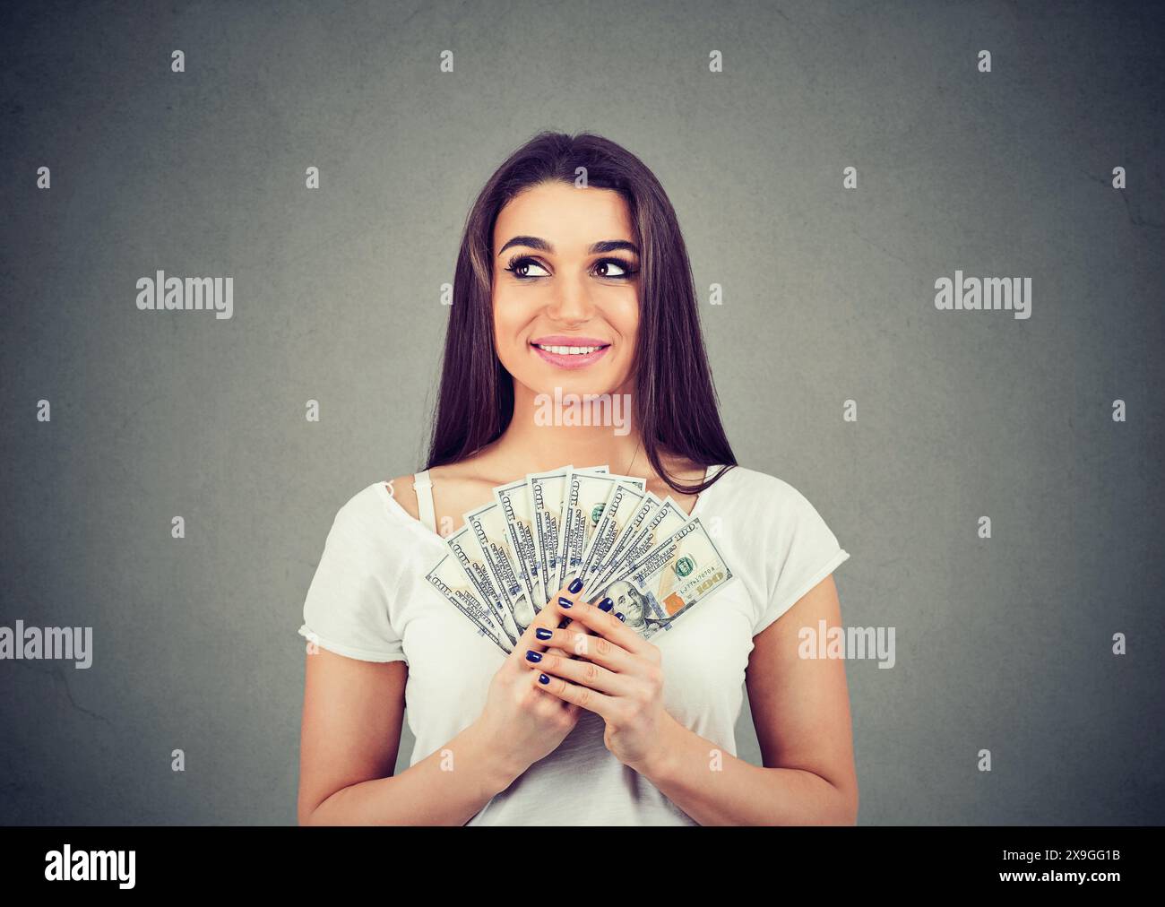 Cute smiling woman with dollar banknotes thinking of financial freedom ...