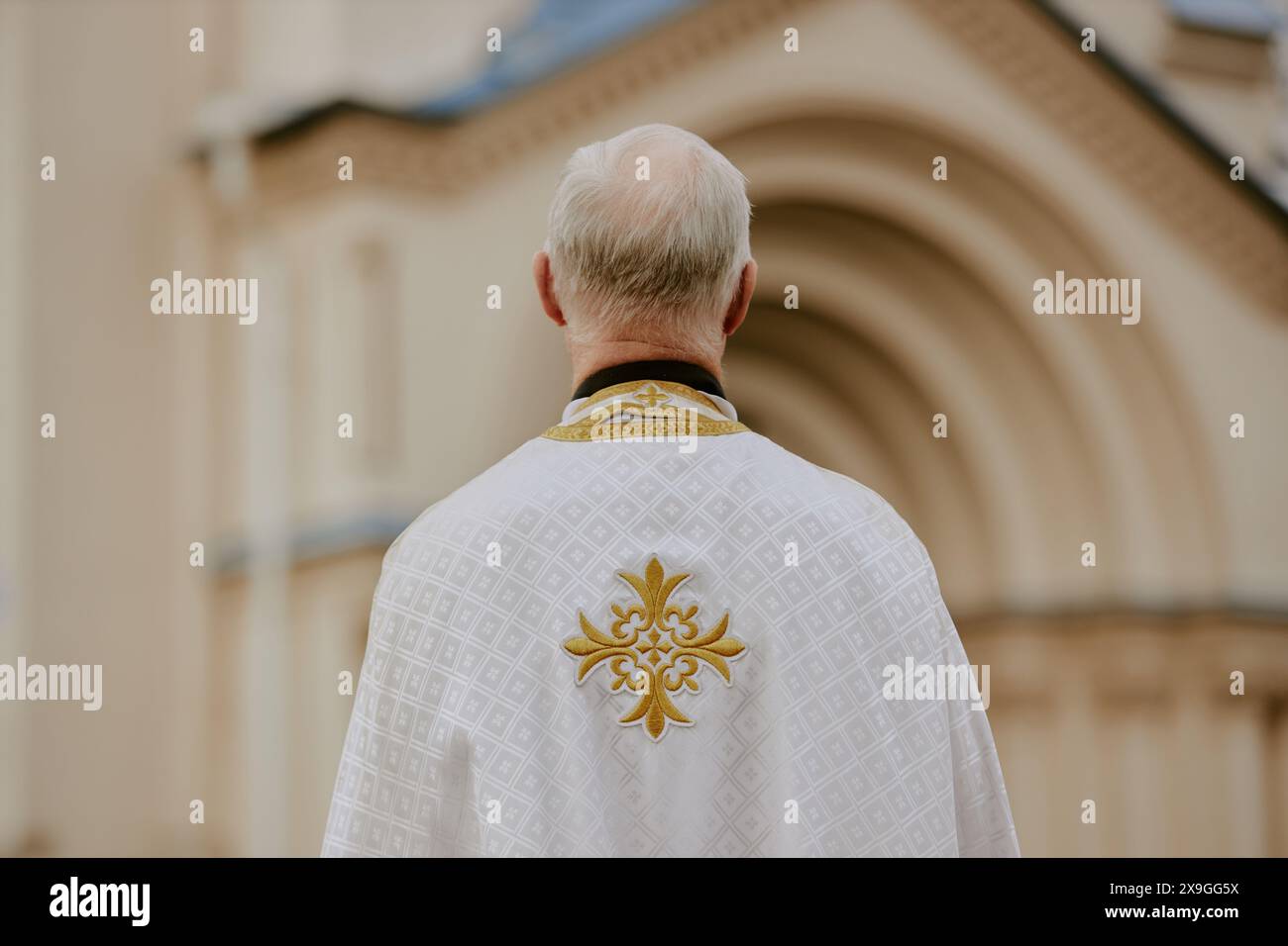 Back view medium shot of unrecognizable senior Catholic priest standing ...