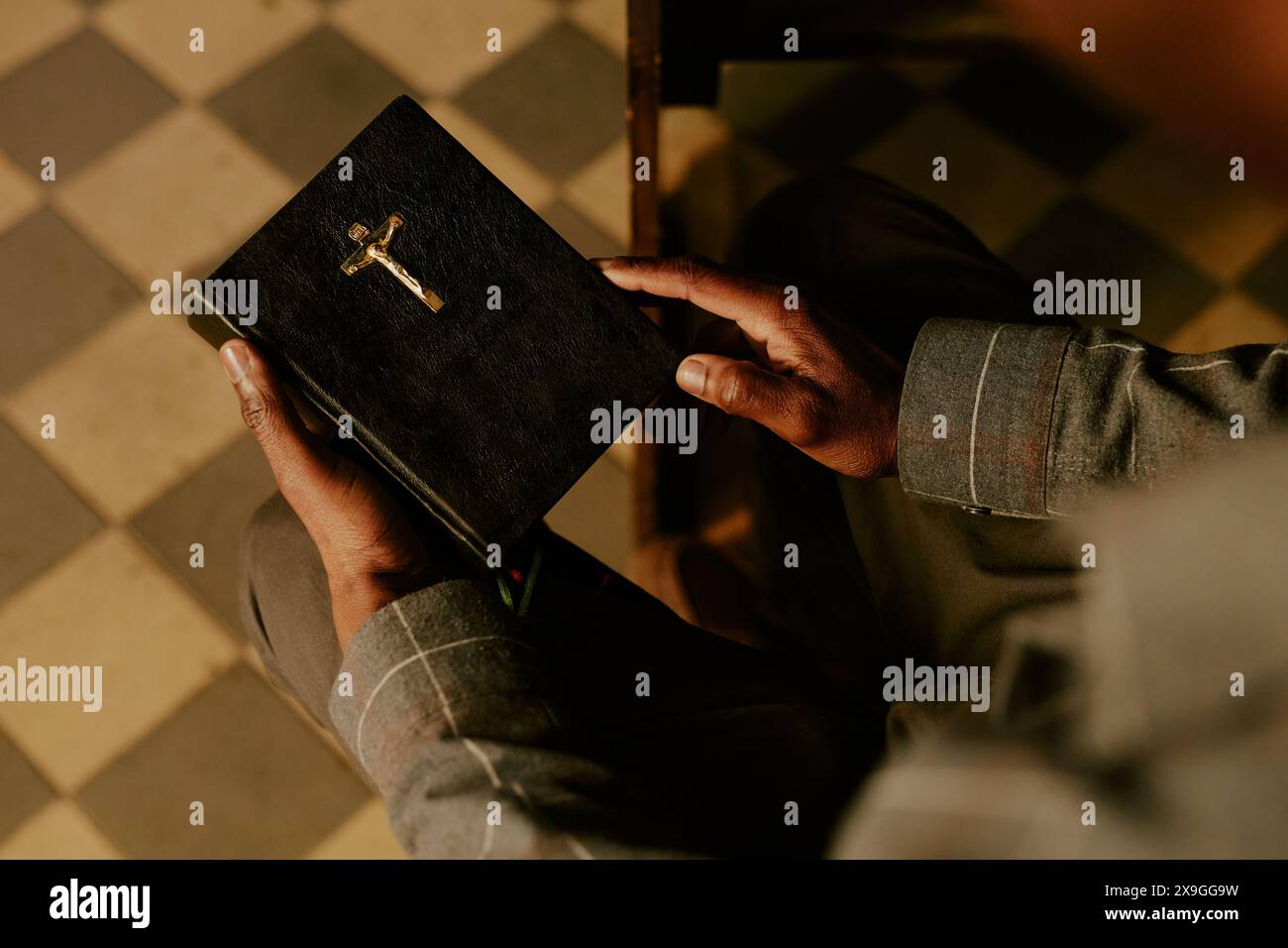 High angle view of hands of unrecognizable Black man sitting on pew in ...