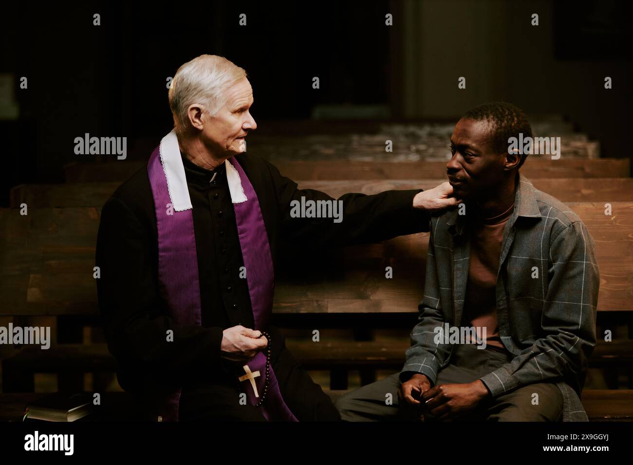 Medium shot of senior Caucasian Catholic priest and young African ...