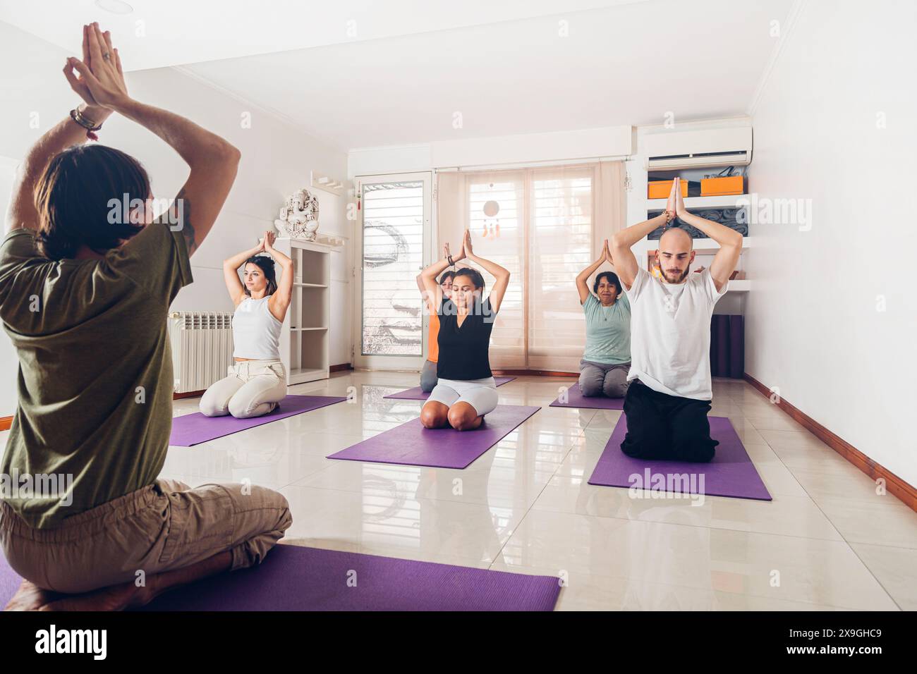 Group of people in a yoga class in the prayer position with raised ...