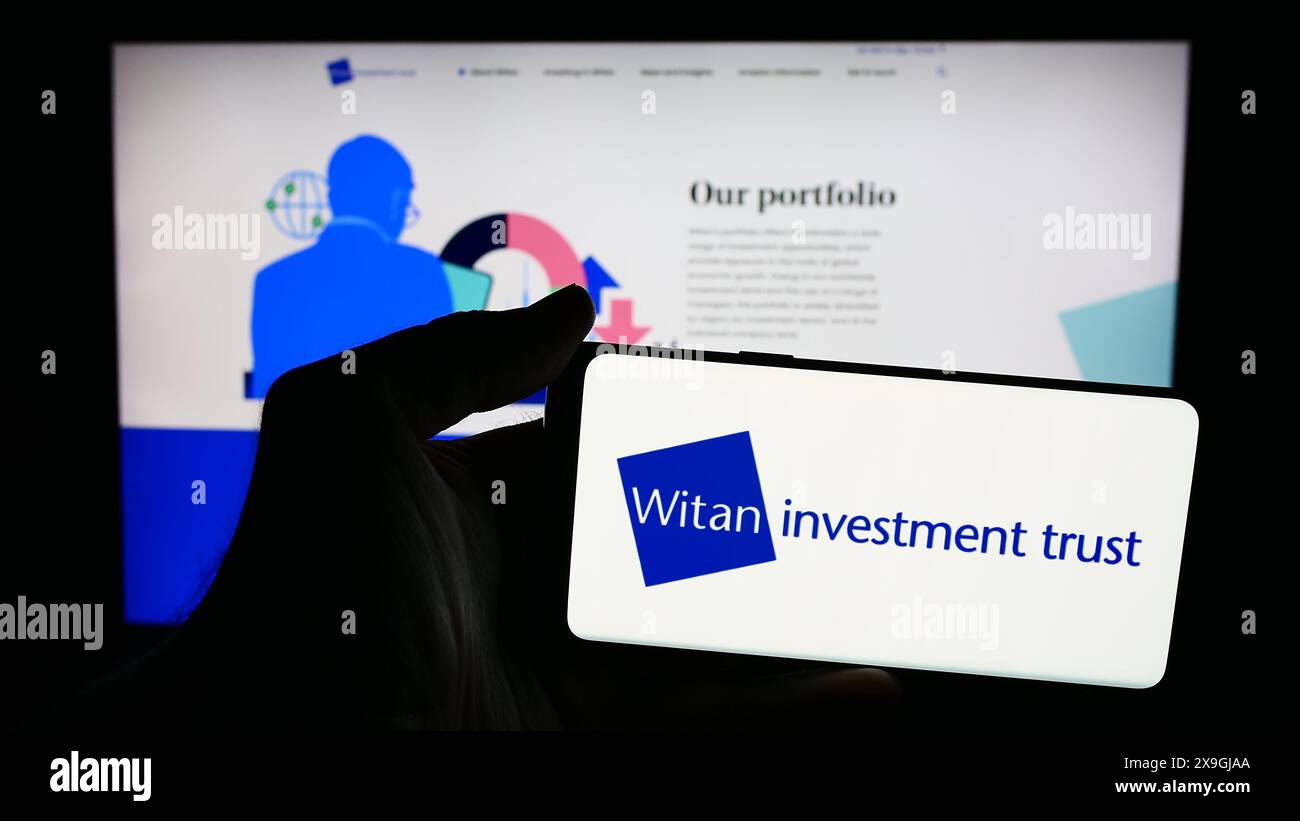 Person holding mobile phone with logo of British company Witan ...