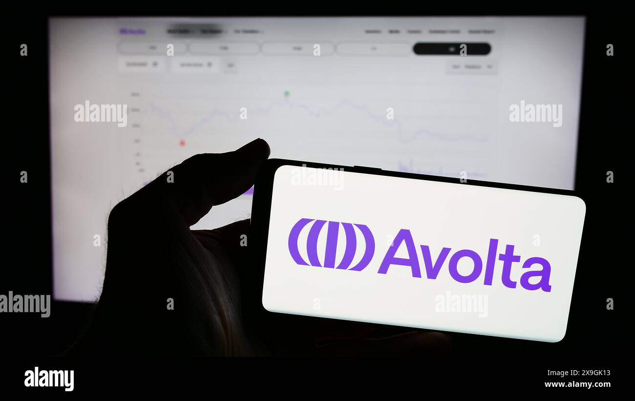 Person holding mobile phone with logo of Swiss travel retail company ...