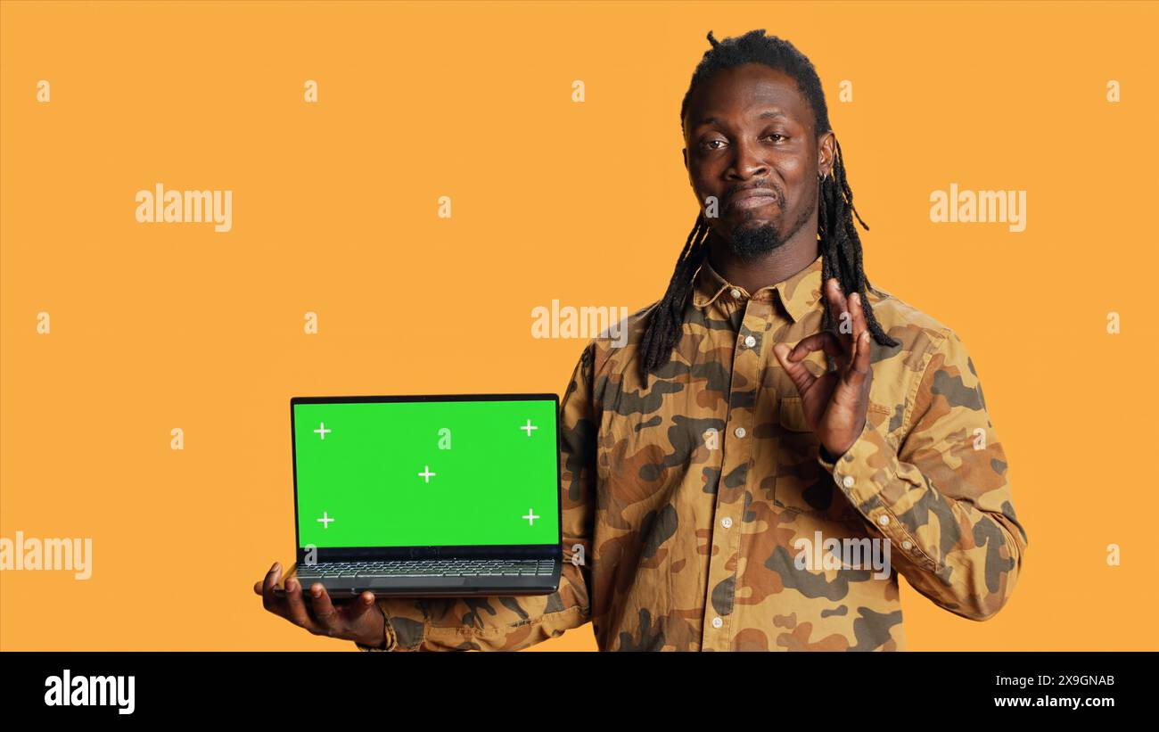 Person having laptop with greenscreen display on camera, posing with ...
