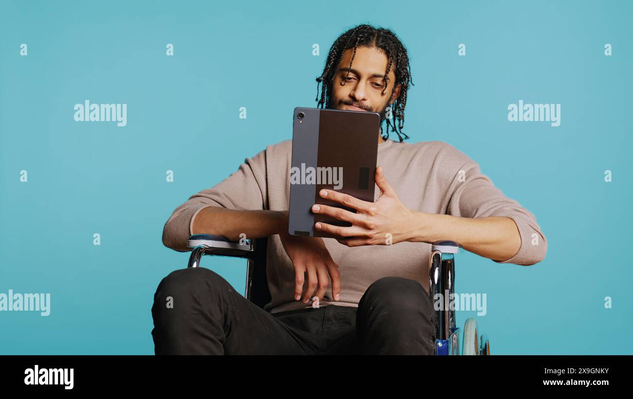 Man in wheelchair chatting with friend over internet videocall using ...