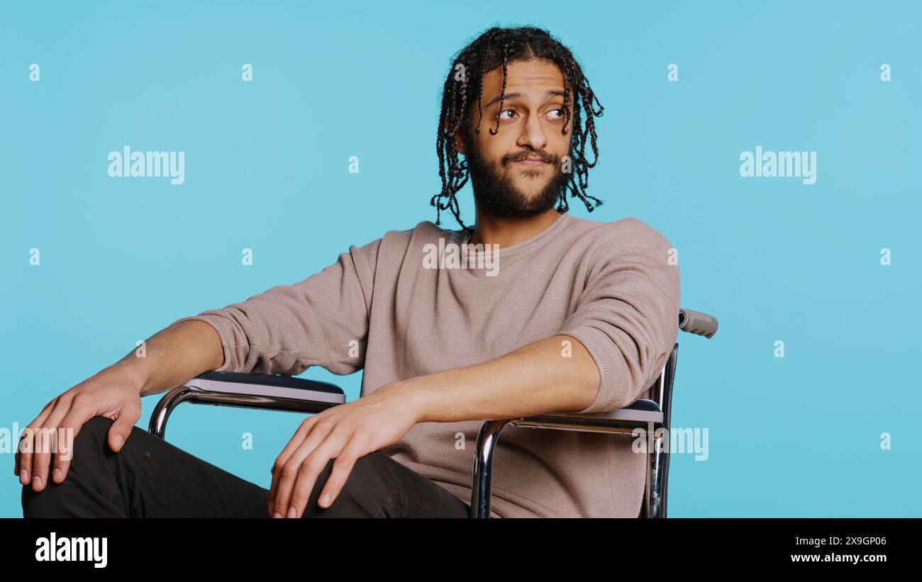 Bored Middle Eastern man with disability in wheelchair impatiently ...