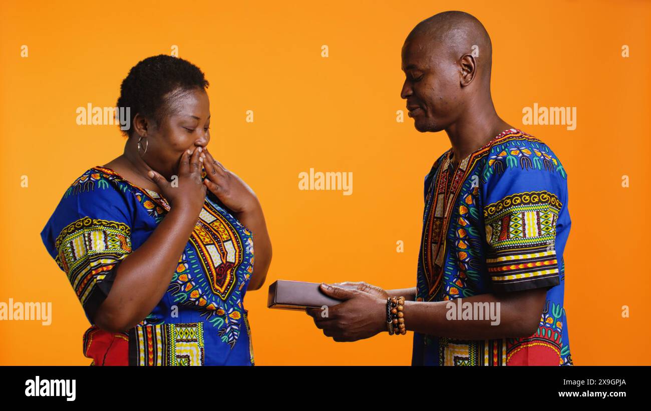 Romantic man offering present with ribbon and bow to his wife, giving ...
