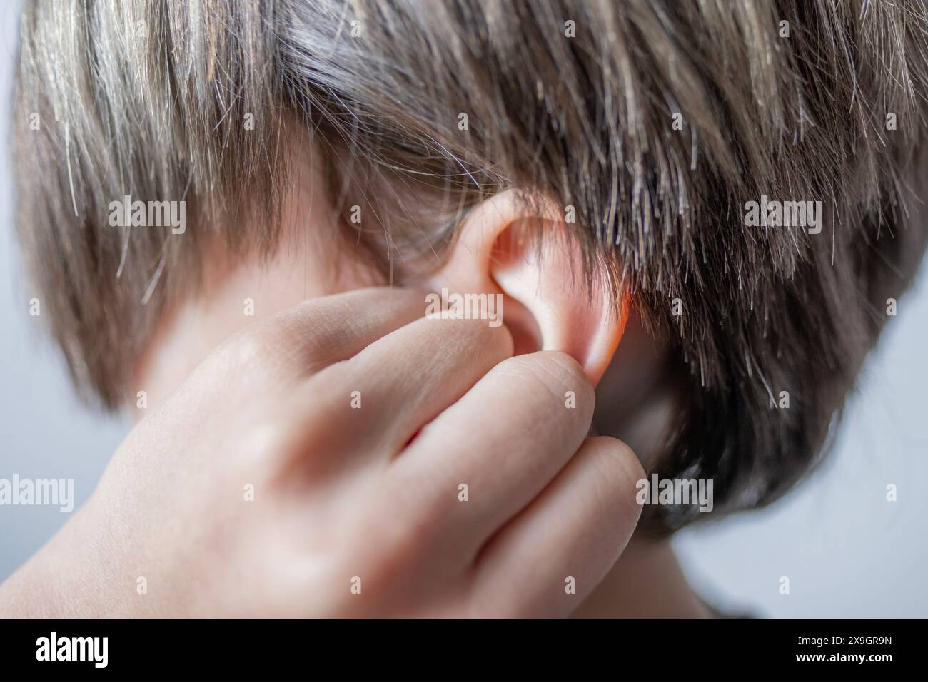 Close-up detail child ear, severe earache, holding onto affected area ...