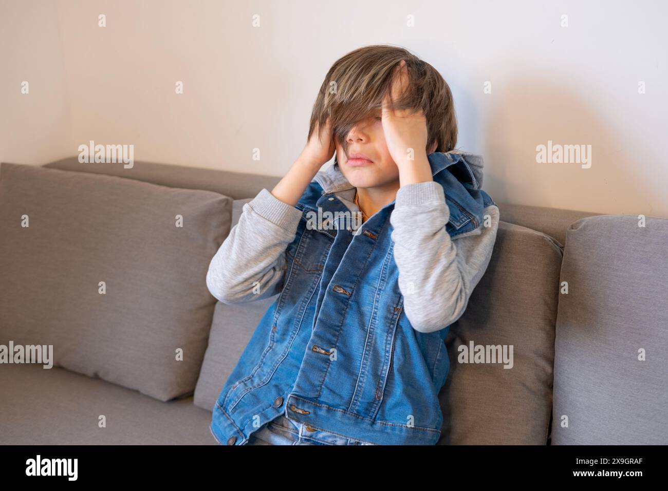 stressed and depressed teenager sits on couch, hiding face, boy ...