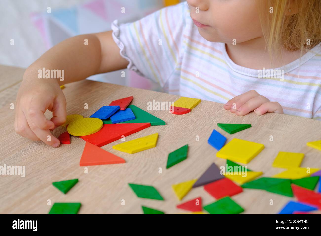 child, toddler, girl plays with colored wooden geometric figures, cubes ...