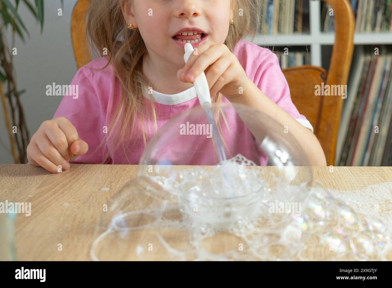 Little girl blows bubbles through plastic straw made of soap foam, kids ...