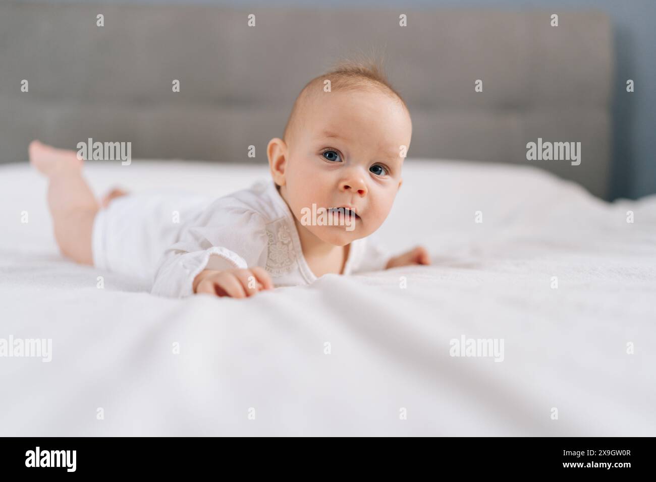 Medium shot of funny newborn baby 4 month laying on stomach developing ...