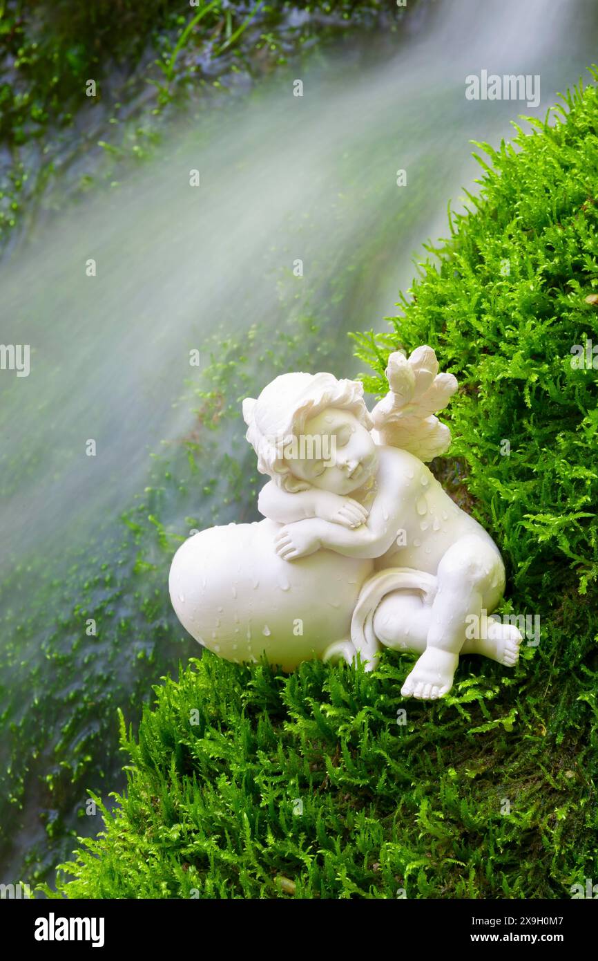 Porcelain angel figurine on moss by a waterfall Stock Photo - Alamy
