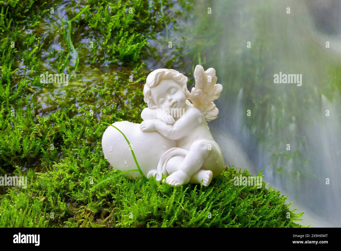 Porcelain angel figurine on moss by a waterfall Stock Photo - Alamy