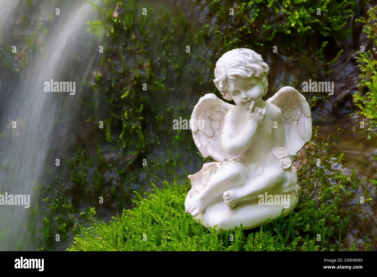 Porcelain angel figurine on moss by a waterfall Stock Photo - Alamy
