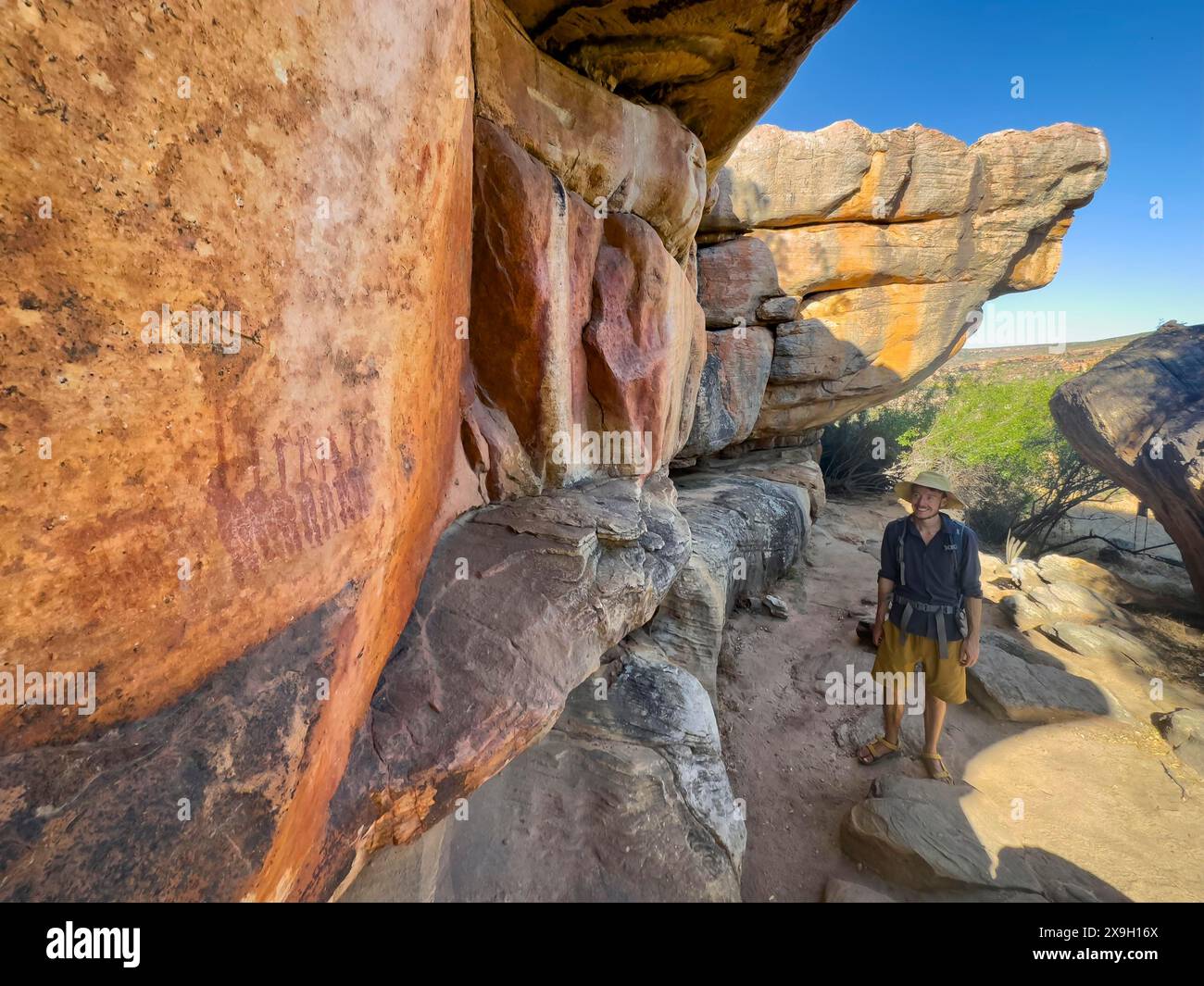 Young man looking at prehistoric depiction of woman on a rock, San rock ...