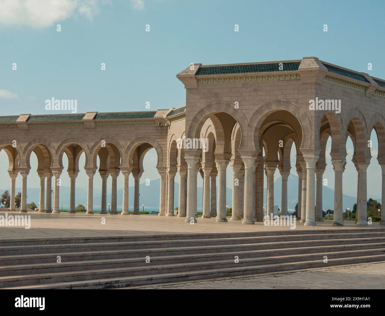 An exterior stone structure with arches and columns under a sunny sky ...