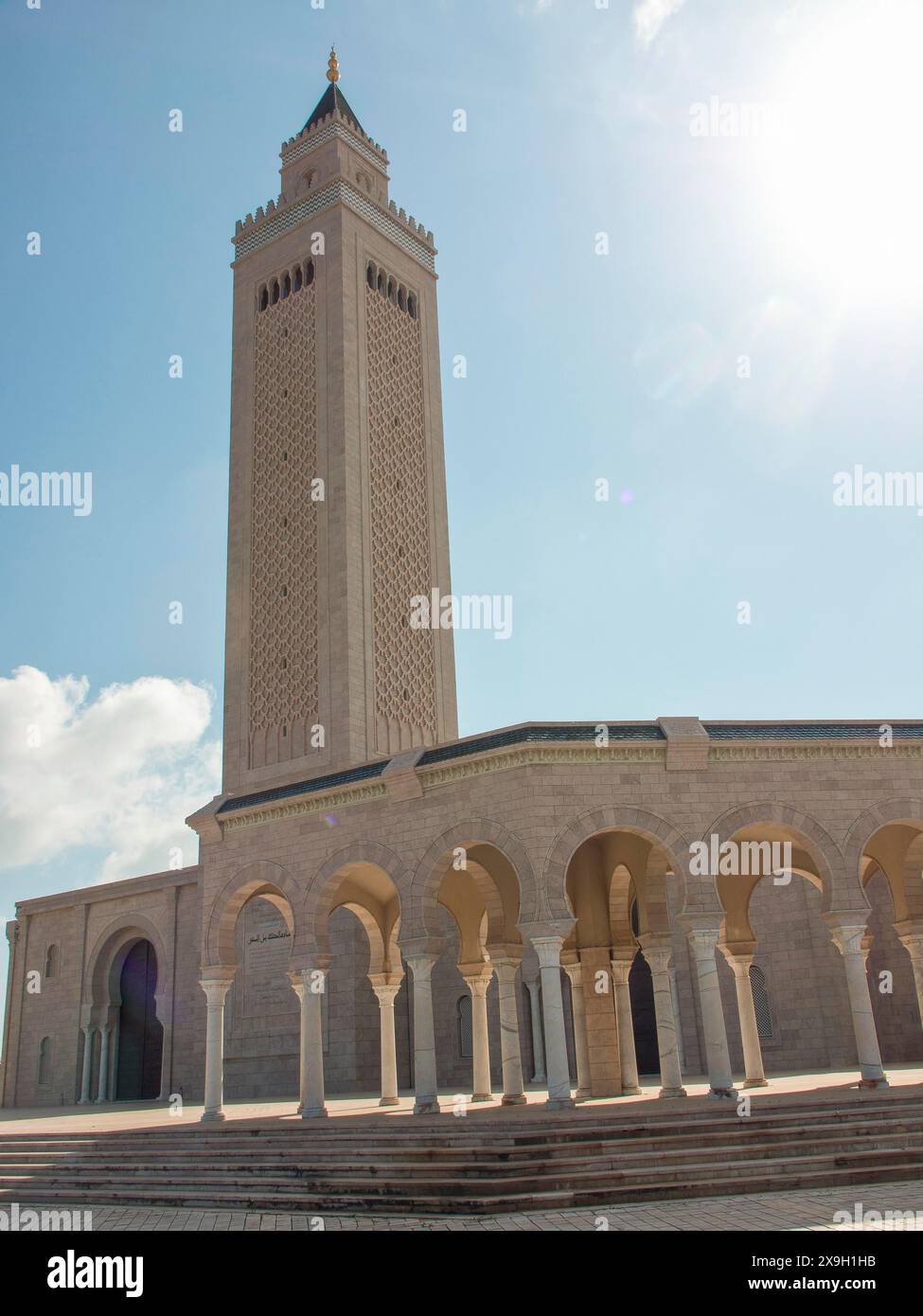 High mosque with minaret and arches, in sunlight, clear line against ...