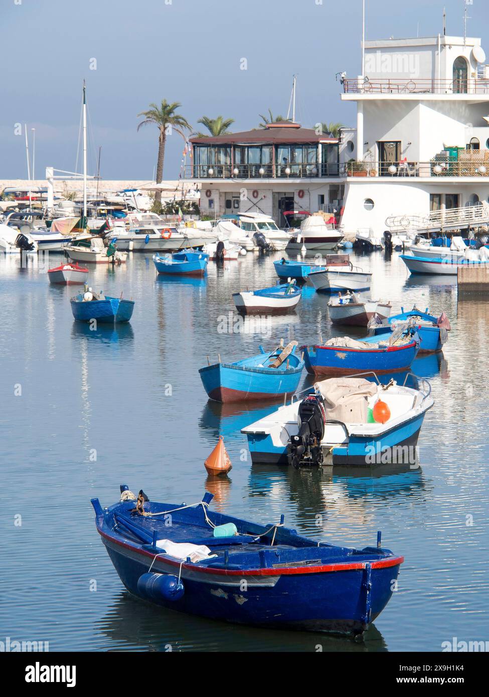 Many colourful boats are in the calm harbour water in front of ...