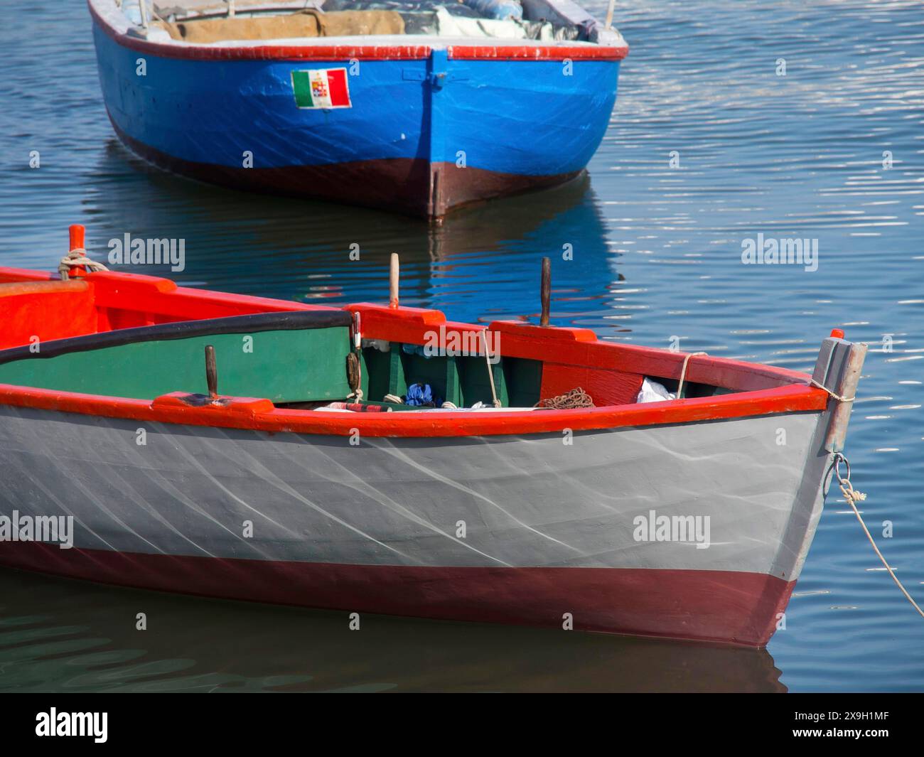 Red and grey fishing boat in the water, slender shapes and calm water ...