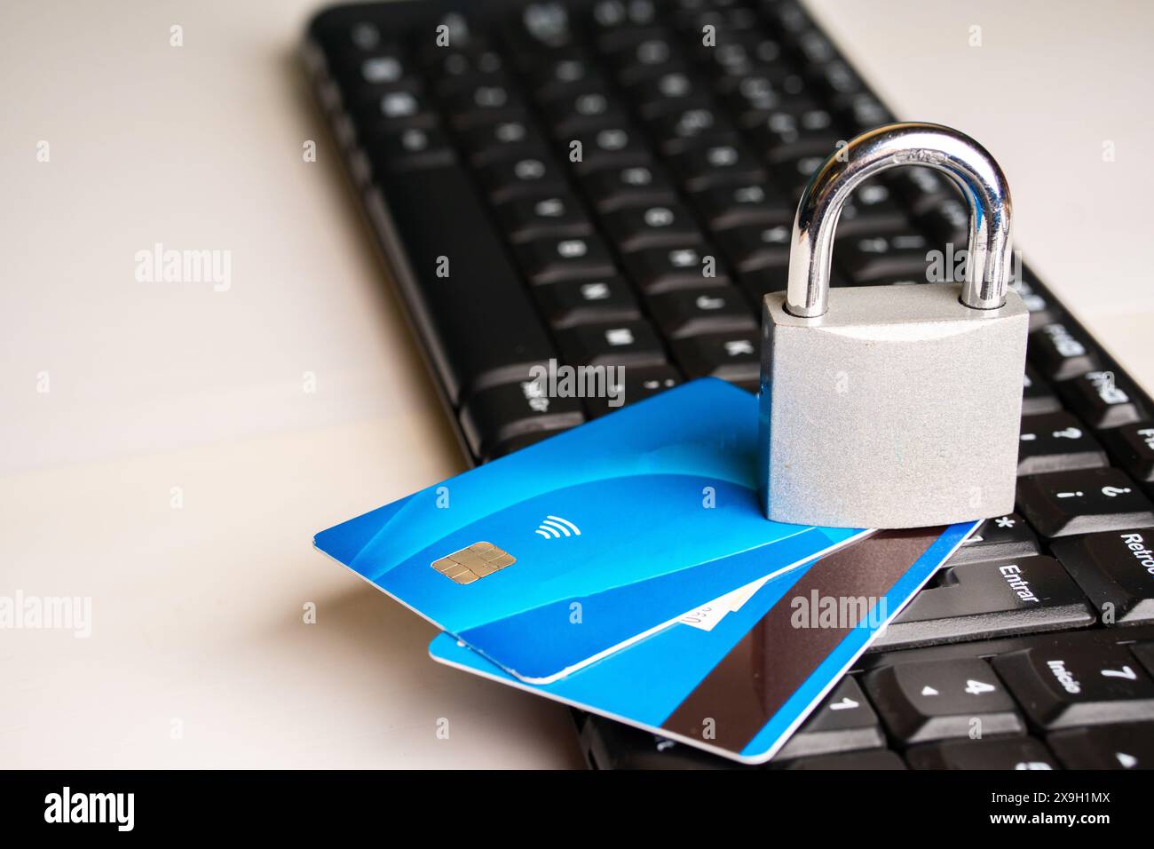 A padlock over a pair of credit cards next to a computer keyboard on a ...