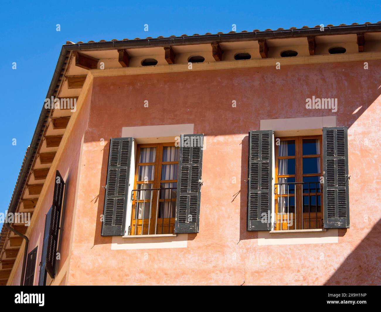 Close-up of a house with open shutters and a balcony in a summer ...